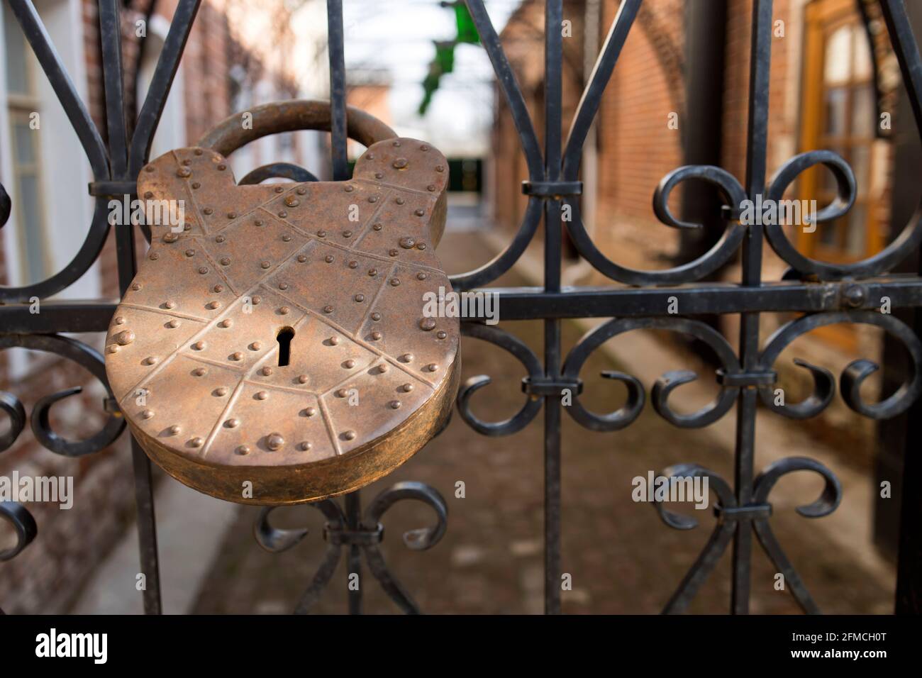 A huge iron barn lock on a metal lattice-gate of the entrance to the ...