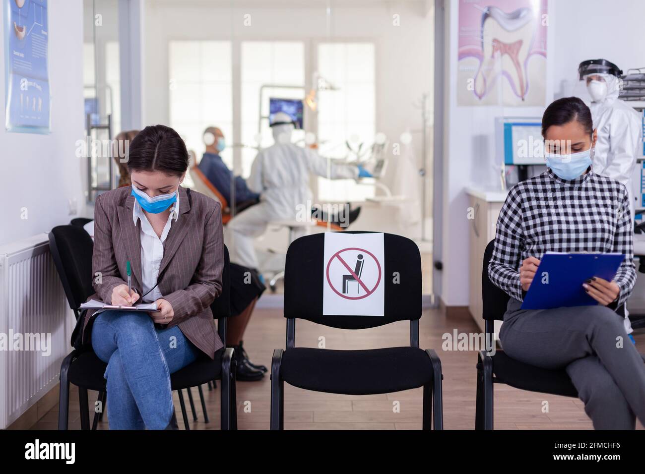 Patient with face protection mask writing on registration form in ...