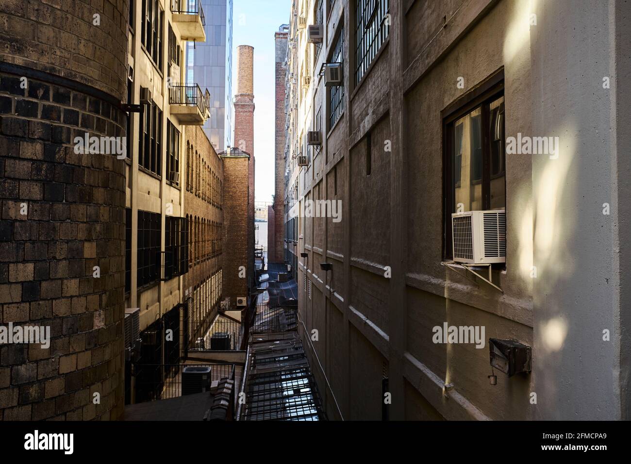 View of dark industrial back alley with brick chimney in background ...