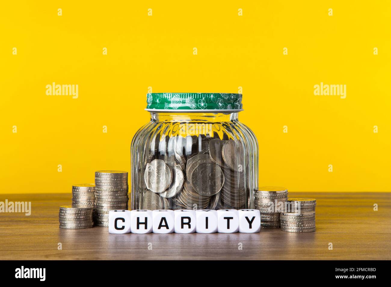 A lot coins in glass money jar with yellow background. Saving for ...