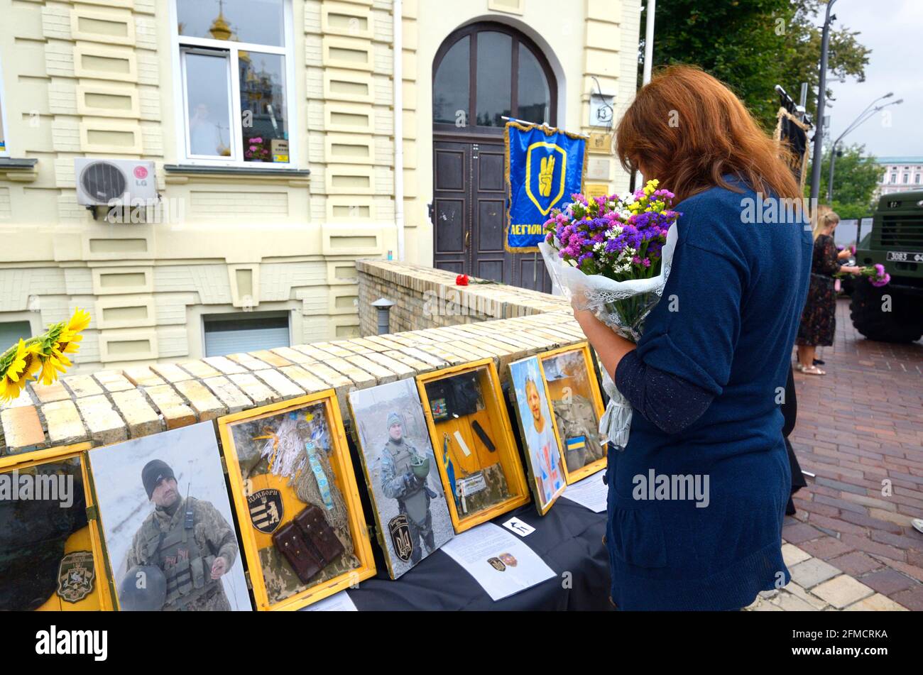 Woman standing in front of the Wall of Remembrance with portraits of ...