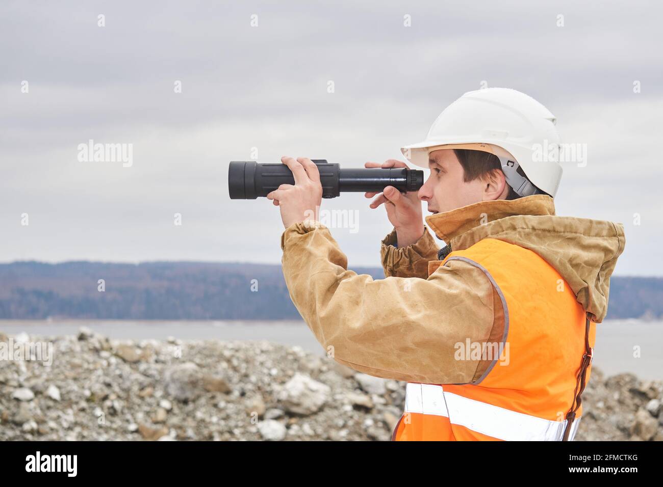 mining or road engineer using a telescope against the background of a ...