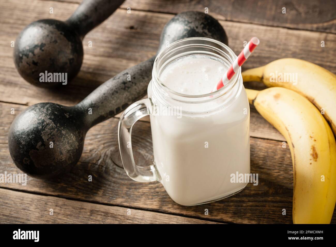 Whey protein cocktail, vintage dumbbells and banana fruit on wooden ...