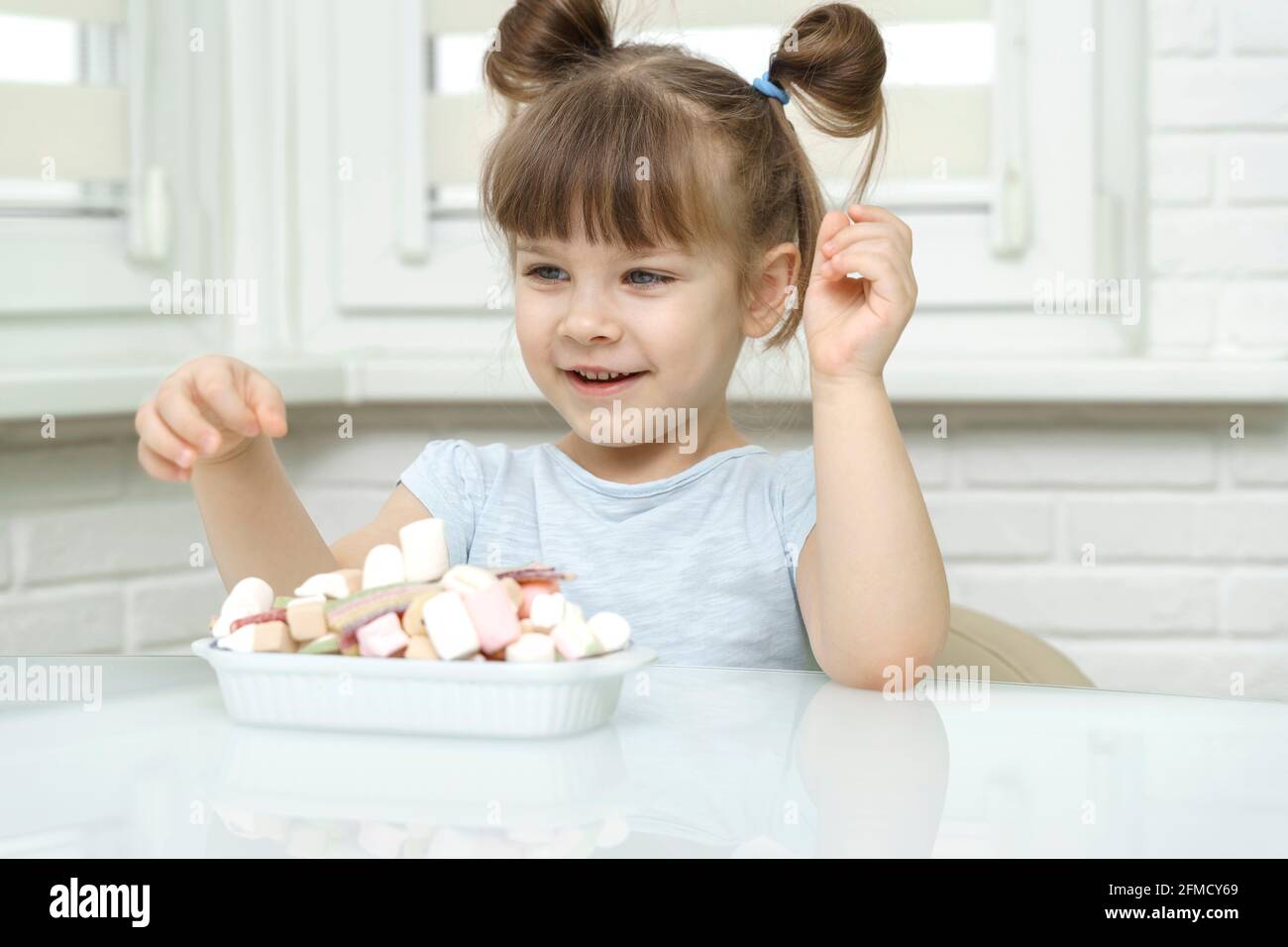 happy contented little girl eating candy from a plate full of sweets ...