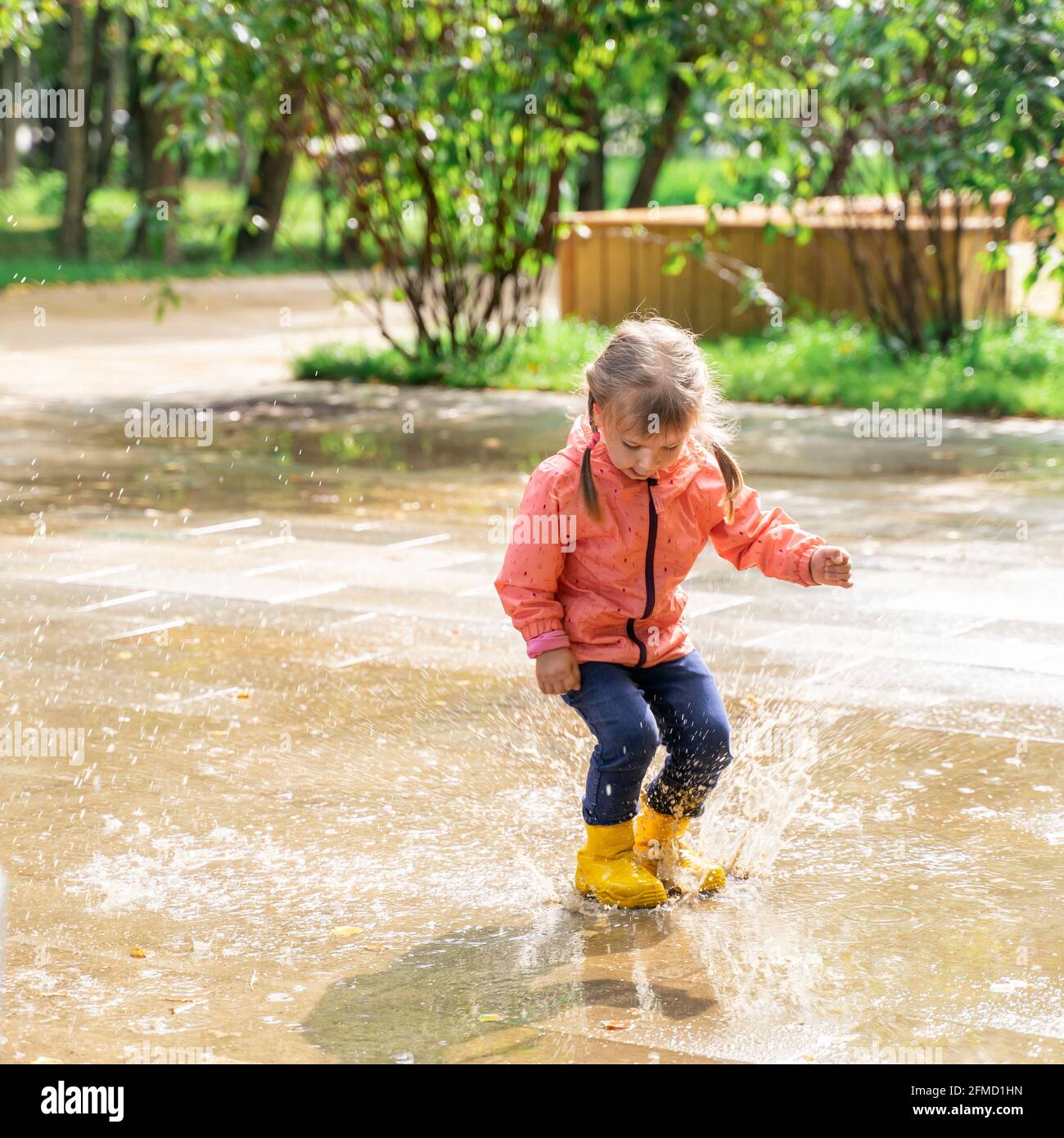 child girl jumping and playing in a puddle after rain Stock Photo - Alamy