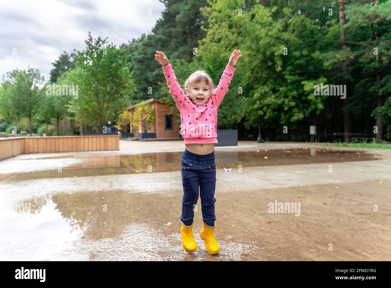 happy child girl running and jumping in puddles after rain in summer ...