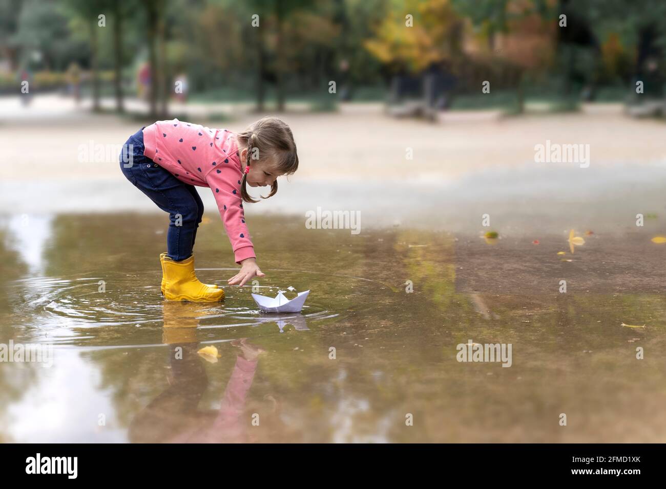 little girl playing with paper boats in puddle Stock Photo - Alamy