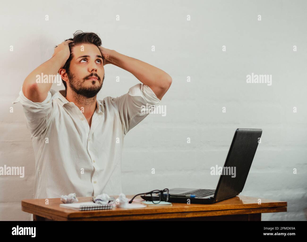 Young Caucasian male gesturing fatigue and stress by holding head with ...