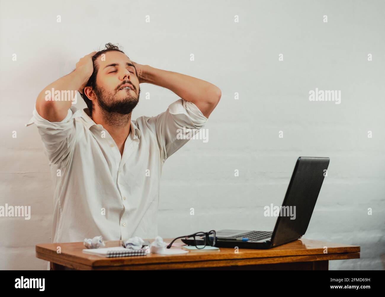 Young Caucasian male gesturing fatigue and stress by holding head with ...