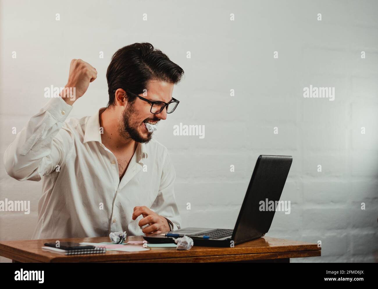Young Caucasian male biting a paper ball and frustrated showing his ...