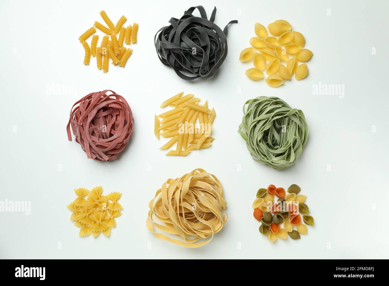 Different uncooked color pasta on white background Stock Photo - Alamy