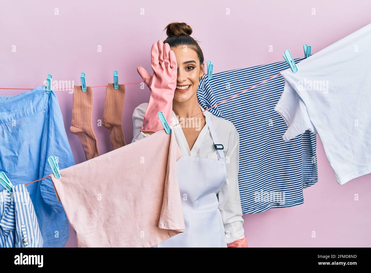 Beautiful brunette young woman washing clothes at clothesline covering ...