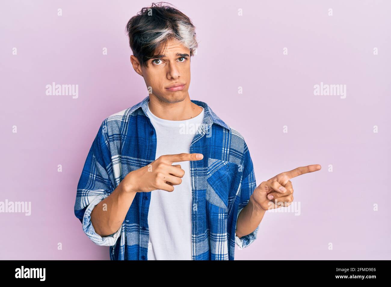 Young hispanic man pointing with fingers to the side depressed and ...
