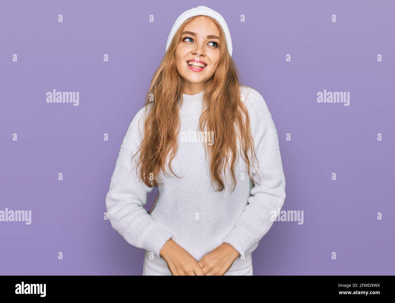 Young caucasian girl wearing wool sweater and winter cap looking away ...