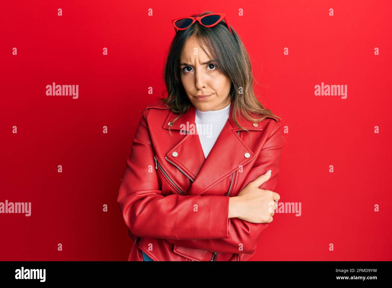 Young brunette woman wearing red leather jacket skeptic and nervous ...