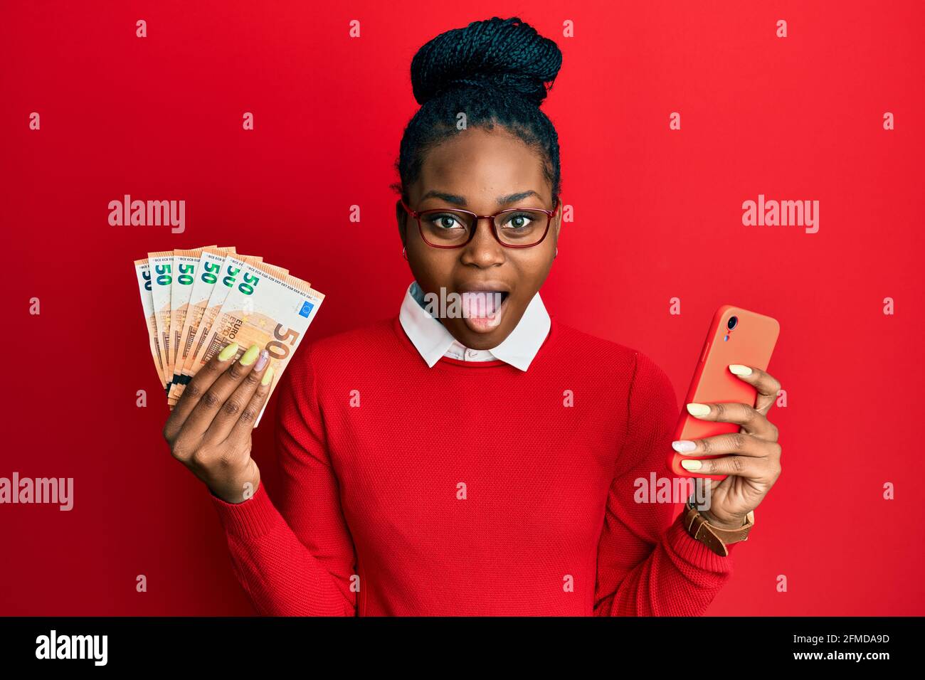 Young african american woman using smartphone holding euro banknotes ...