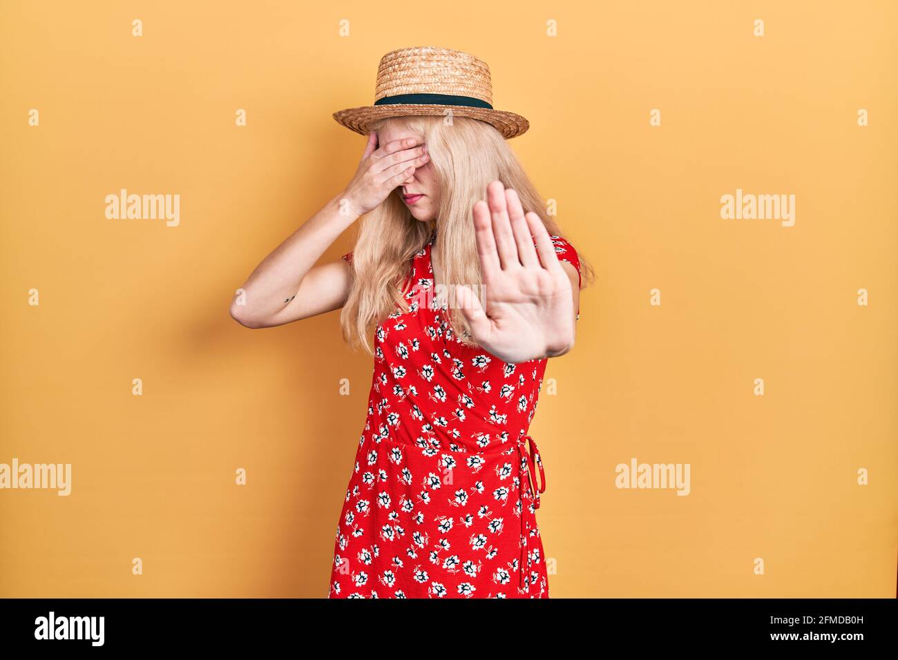 Beautiful caucasian woman with blond hair wearing summer hat covering ...