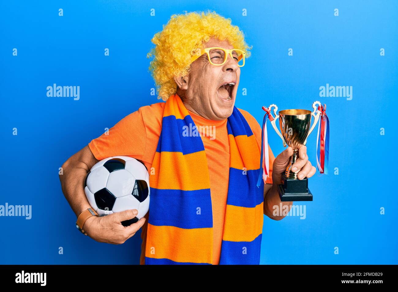 Senior hispanic man football hooligan cheering game holding ball and ...