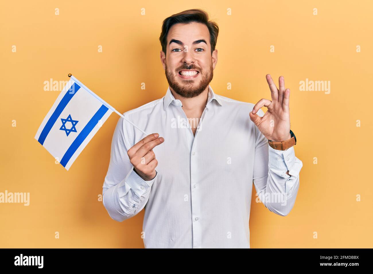 Handsome caucasian man with beard holding israel flag doing ok sign ...