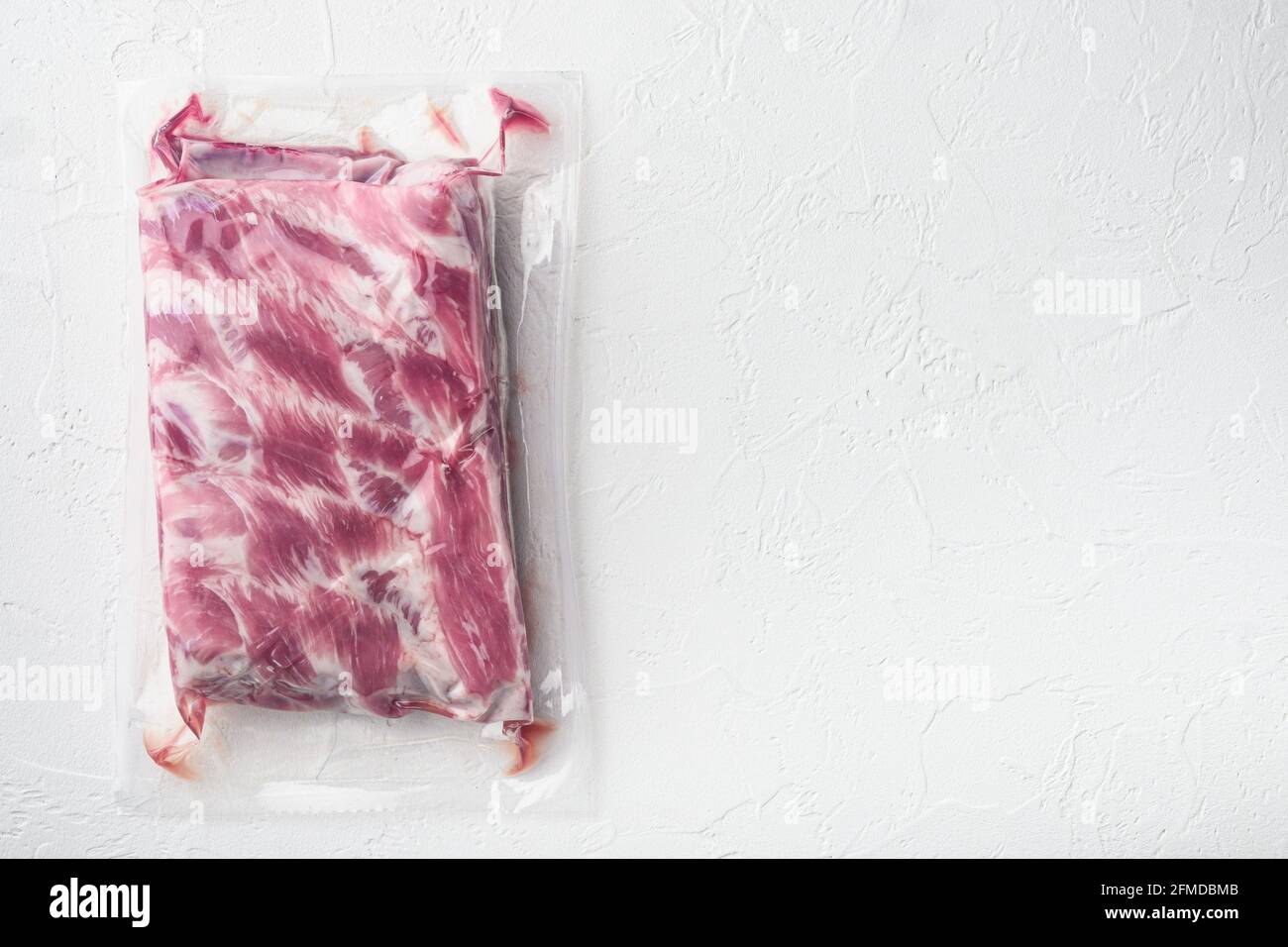 Vacuum packaging with raw pork rib set, on white stone background, top ...