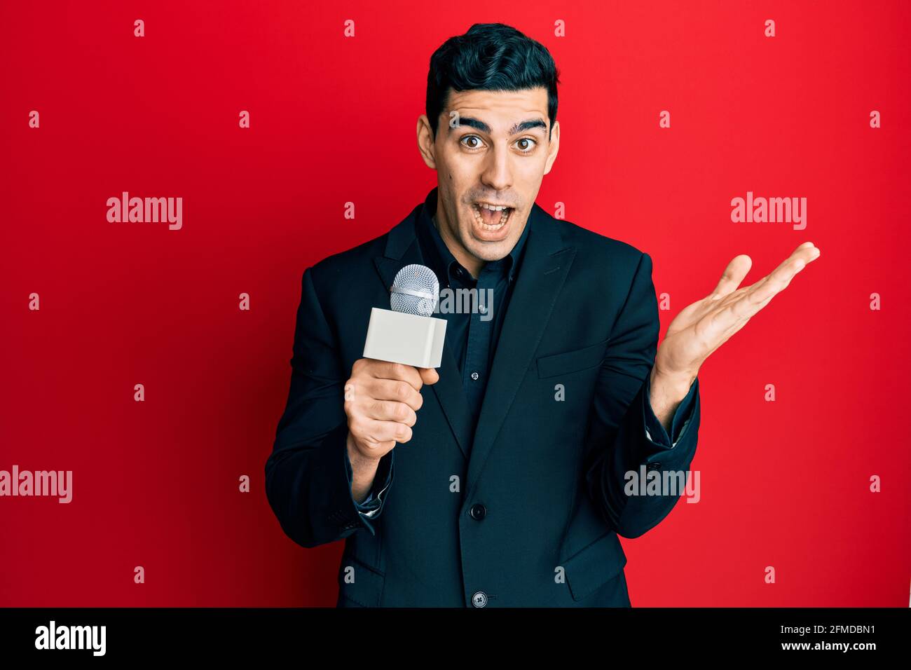 Handsome hispanic man holding reporter microphone celebrating victory ...