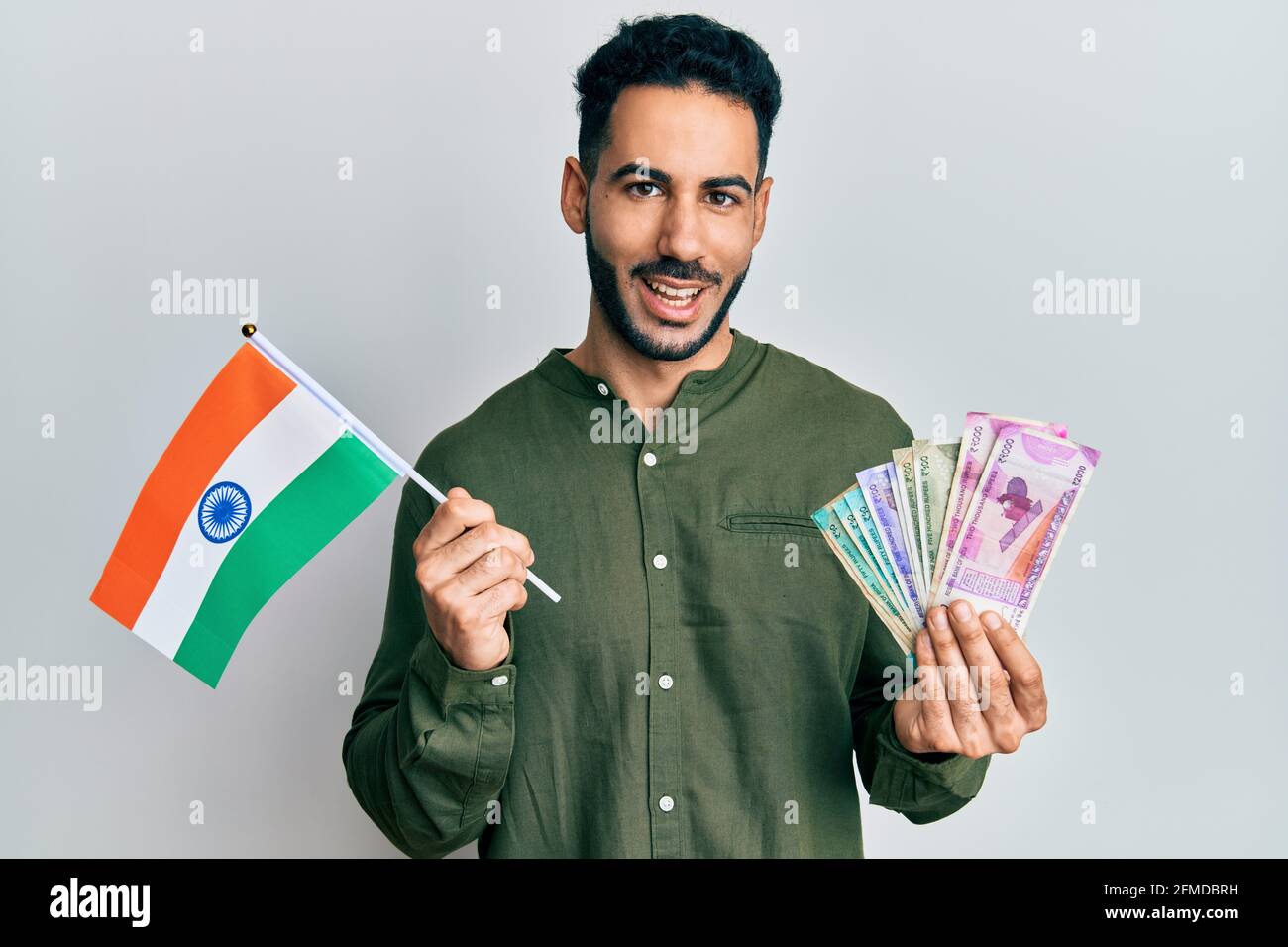 Young hispanic man holding india flag and rupee banknotes smiling and ...