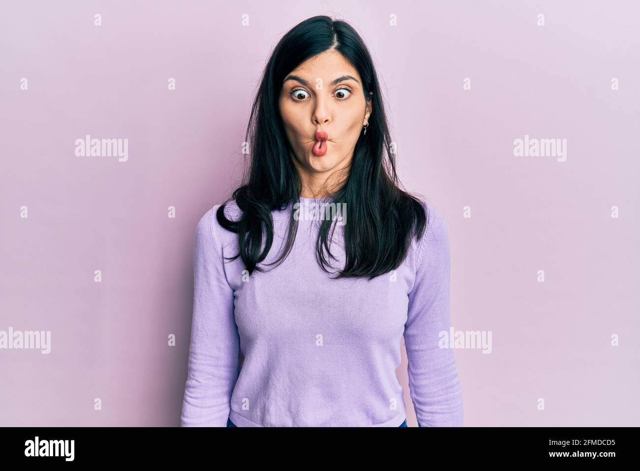 Young hispanic woman wearing casual clothes making fish face with lips ...