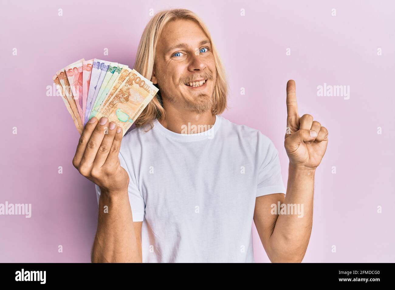Caucasian young man with long hair holding philippine peso banknotes ...