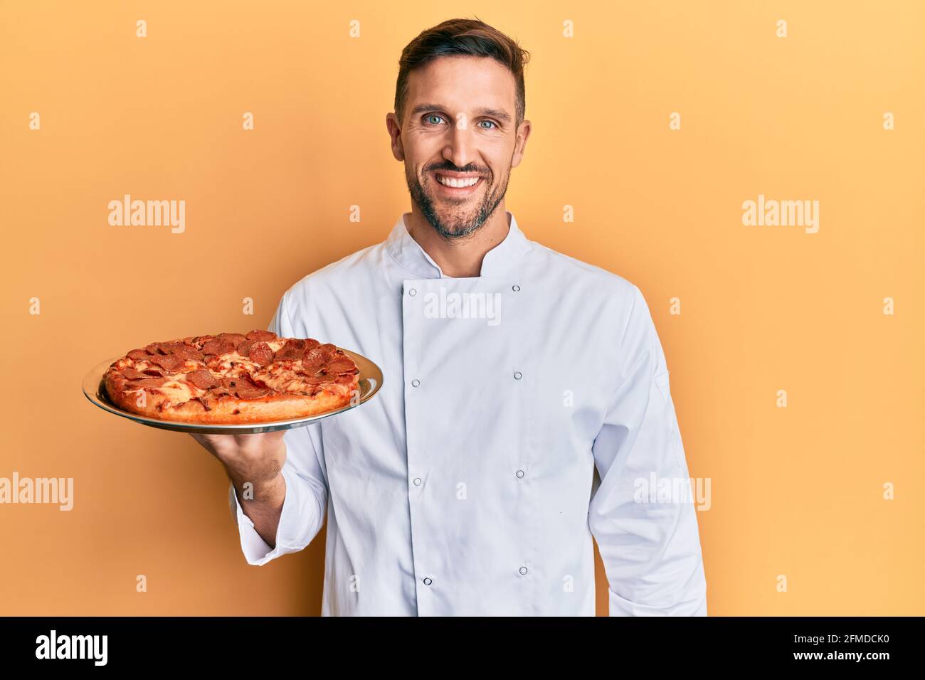 Handsome man with beard professional cook holding italian pizza looking ...