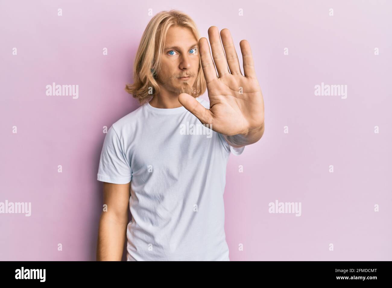 Caucasian young man with long hair wearing casual white t shirt doing ...