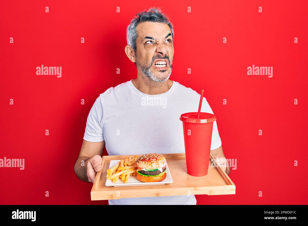 Handsome middle age man with grey hair eating a tasty classic burger ...