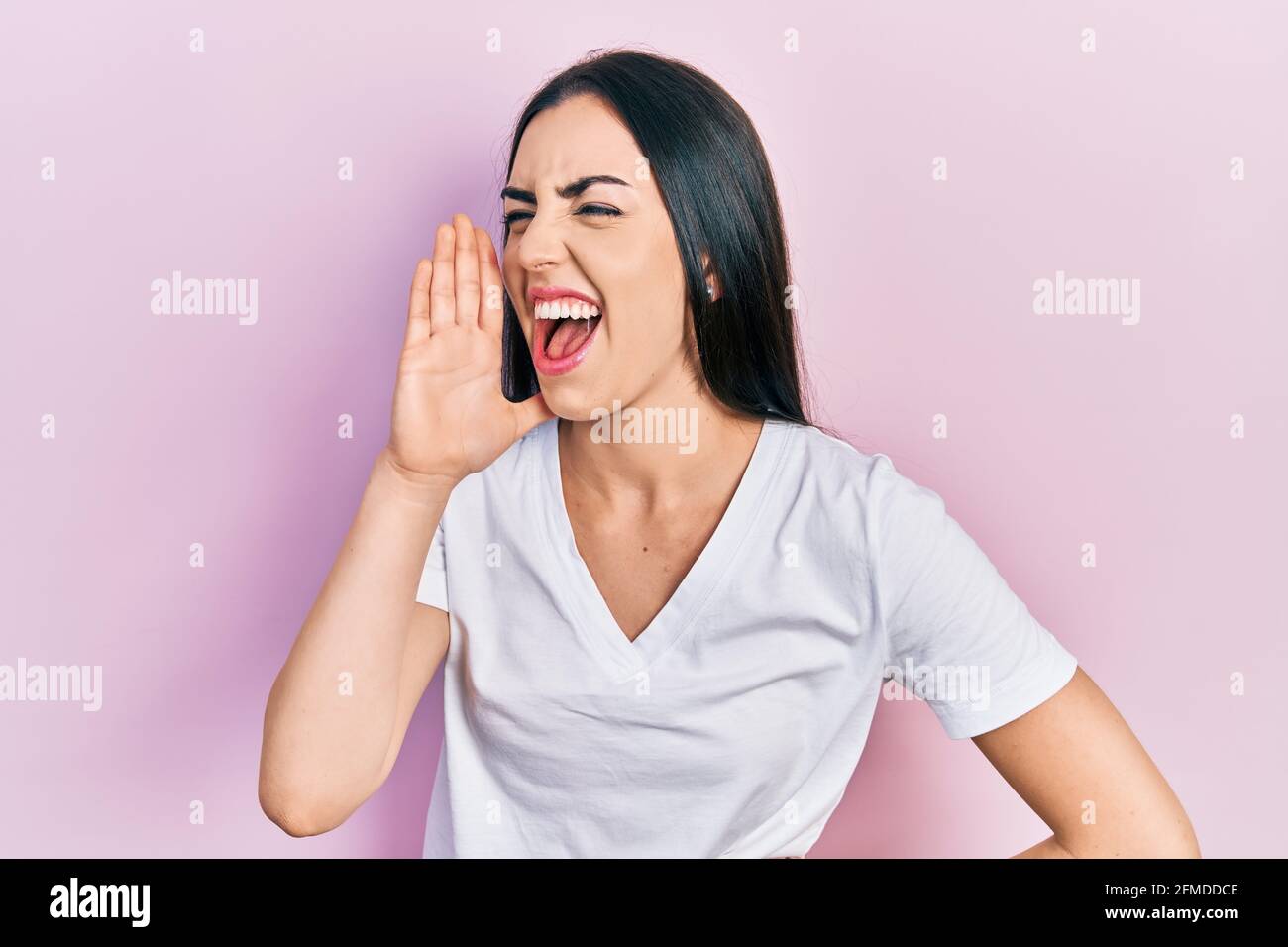 Beautiful woman with blue eyes wearing casual white t shirt shouting ...