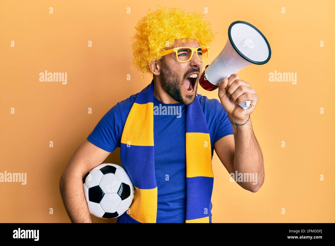Young hispanic man football supporter holding soccer ball using ...