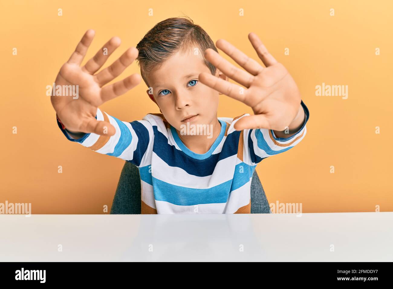 Adorable caucasian kid wearing casual clothes sitting on the table ...