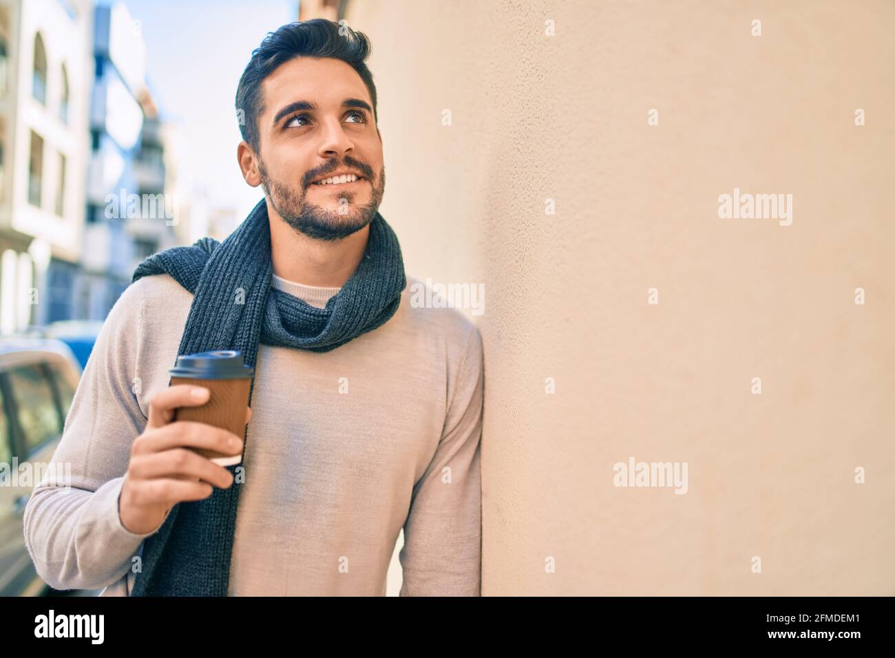 Young hispanic man smiling happy drinking take away coffee at the city ...