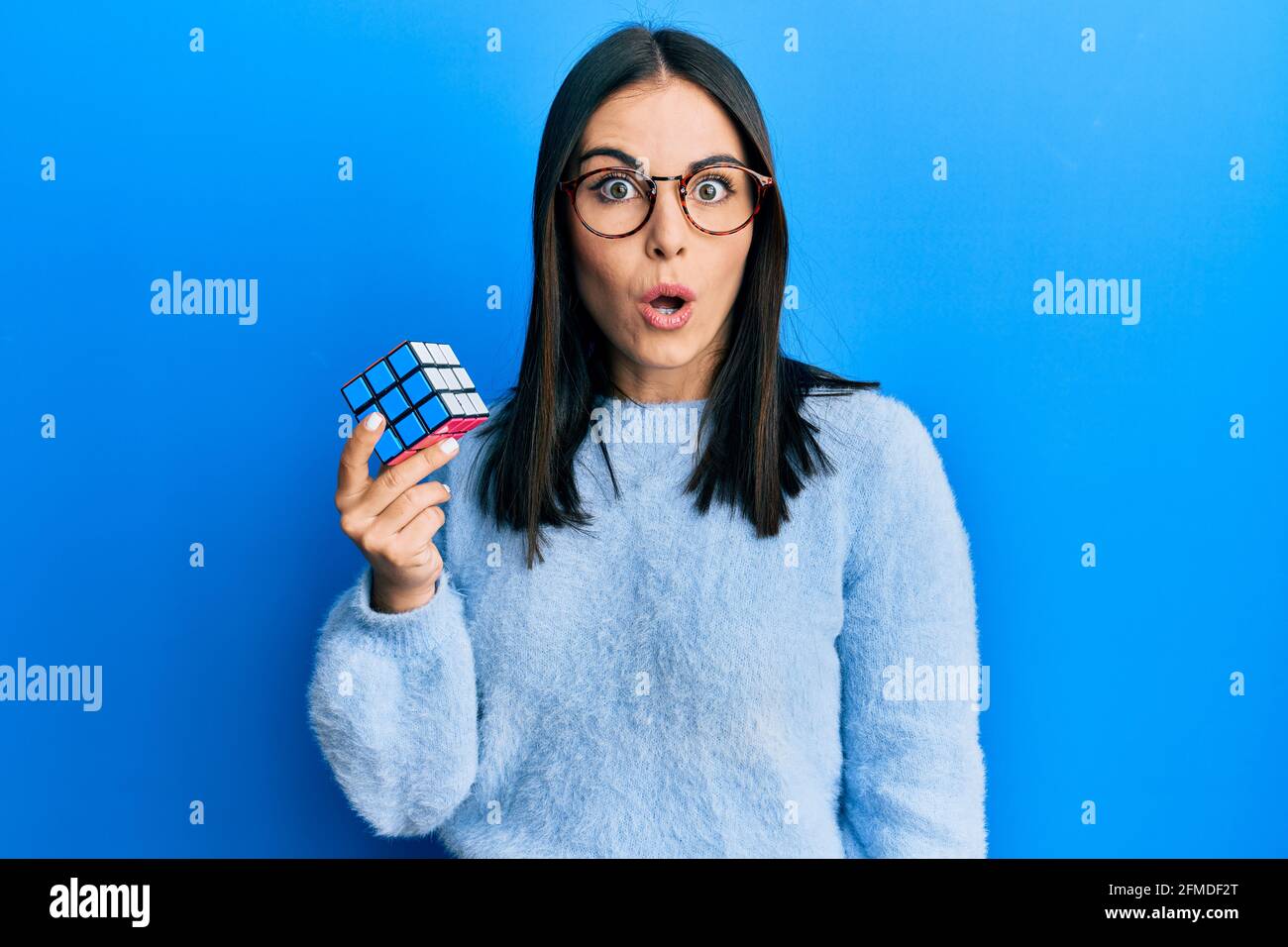 Young brunette woman playing colorful puzzle cube intelligence game ...