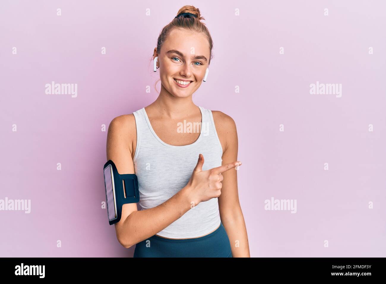 Beautiful blonde sport woman wearing arm band and earphones smiling ...