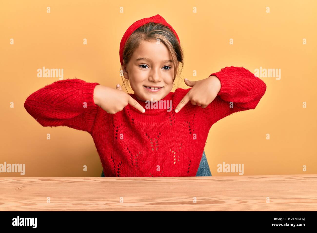 Little beautiful girl wearing casual clothes sitting on the table ...