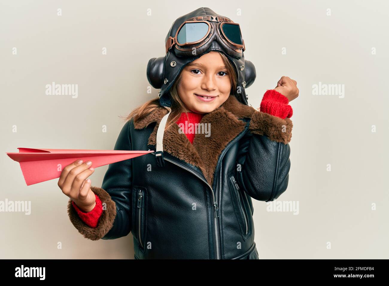 Little beautiful girl wearing pilot uniform holding paper plane ...