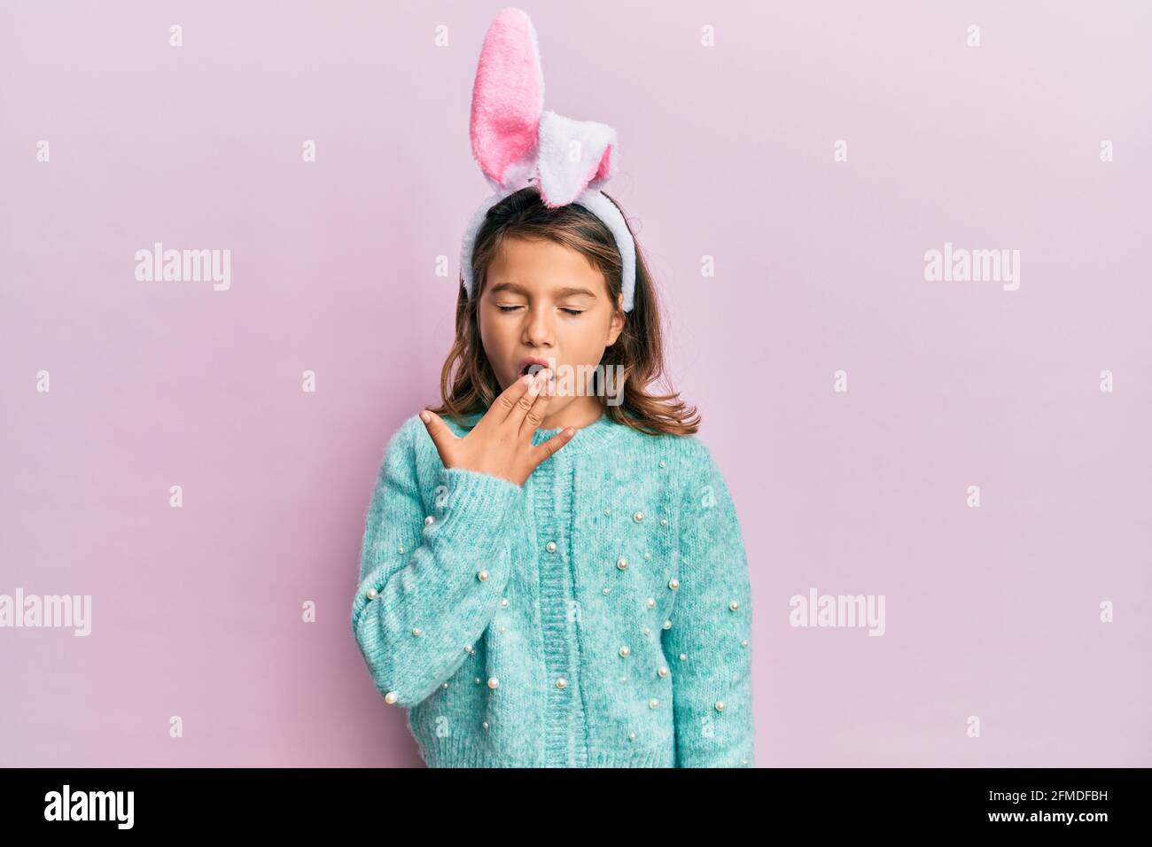 Little beautiful girl wearing cute easter bunny ears bored yawning ...