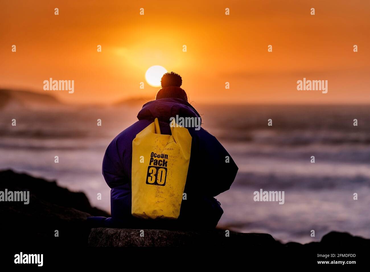 A walker wearing a bobble hat and an Ocean Pack 30 backpack sitting and ...