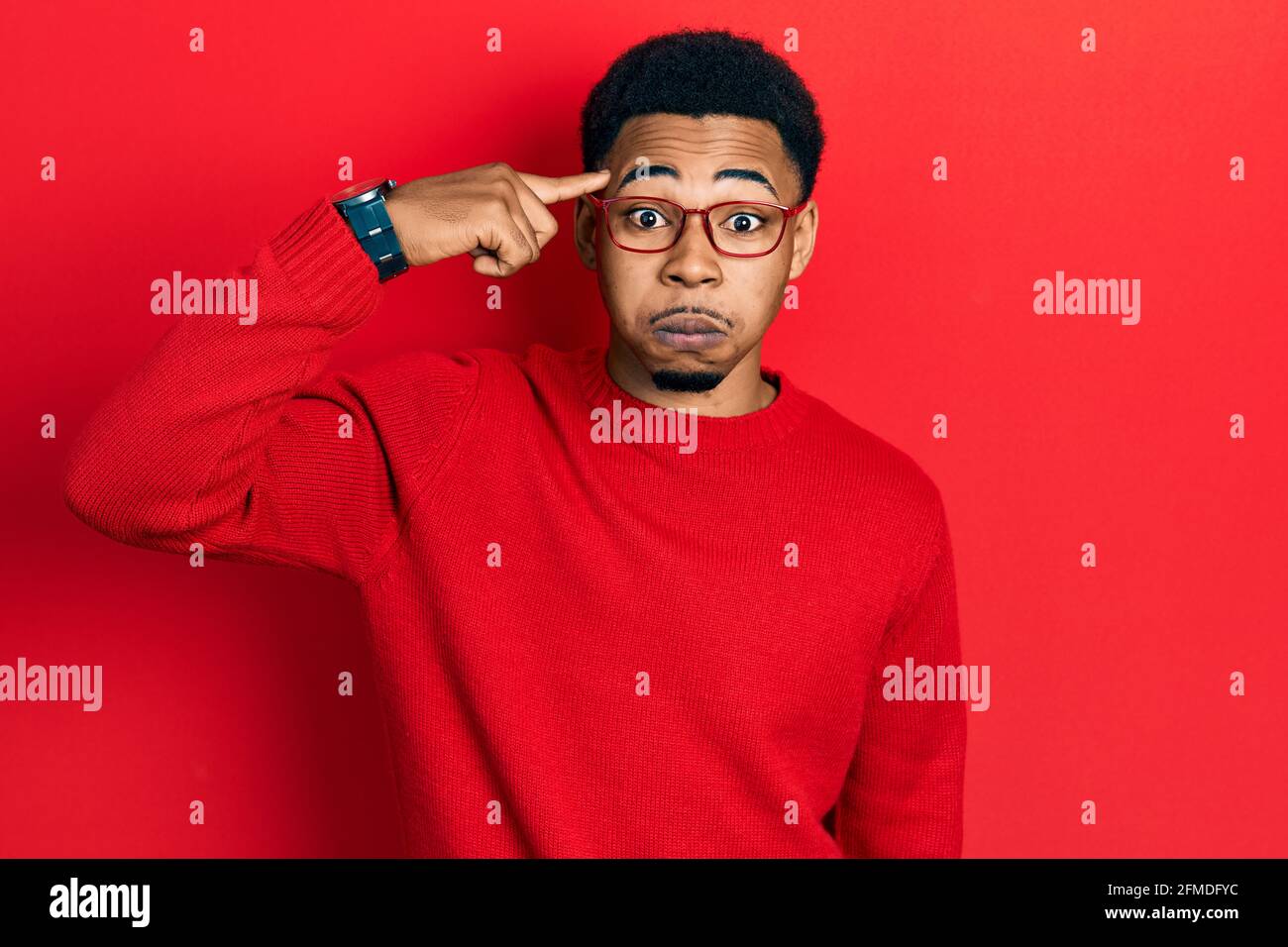 Young african american man pointing head with finger puffing cheeks ...