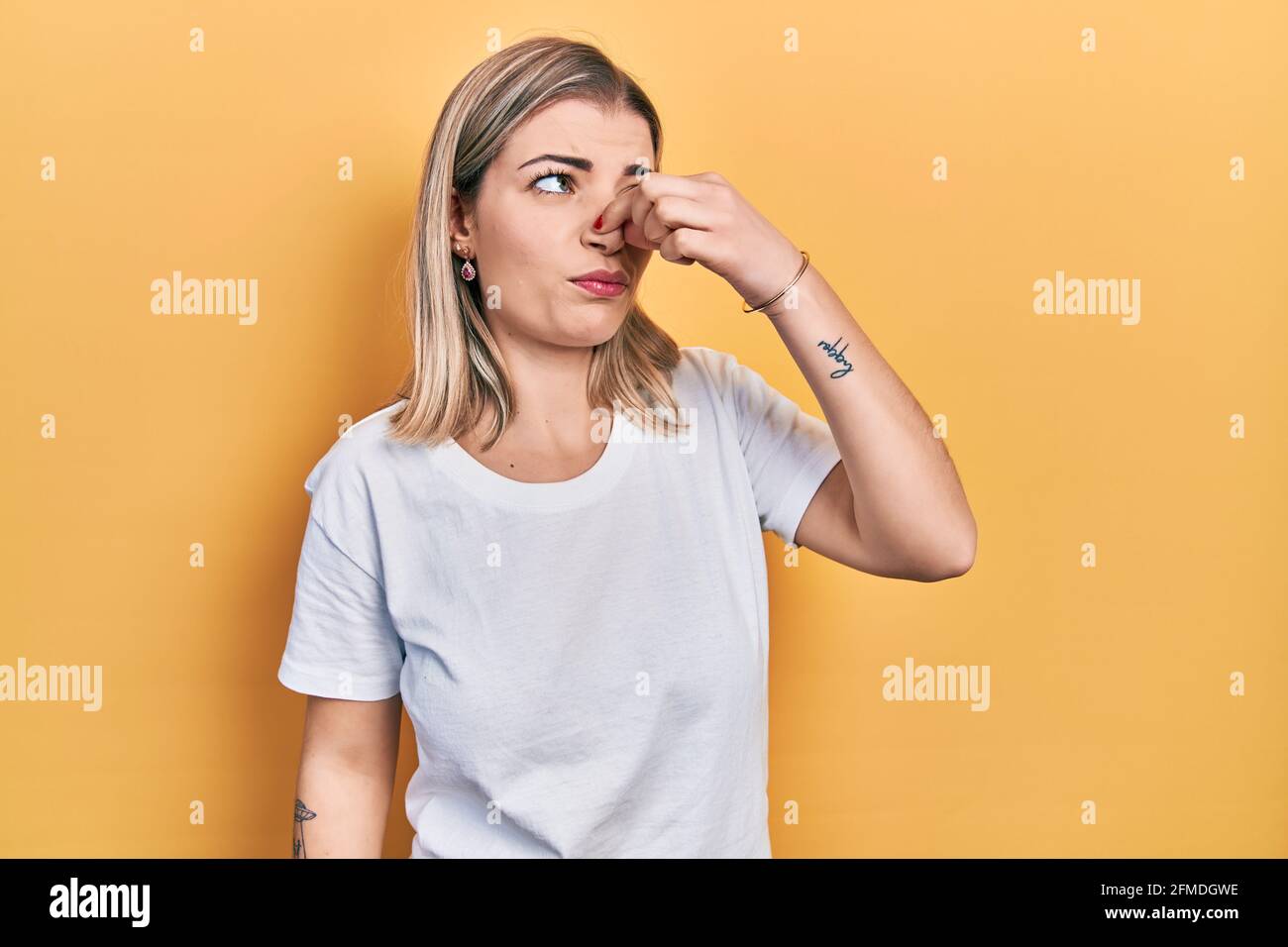 Beautiful caucasian woman wearing casual white t shirt smelling ...