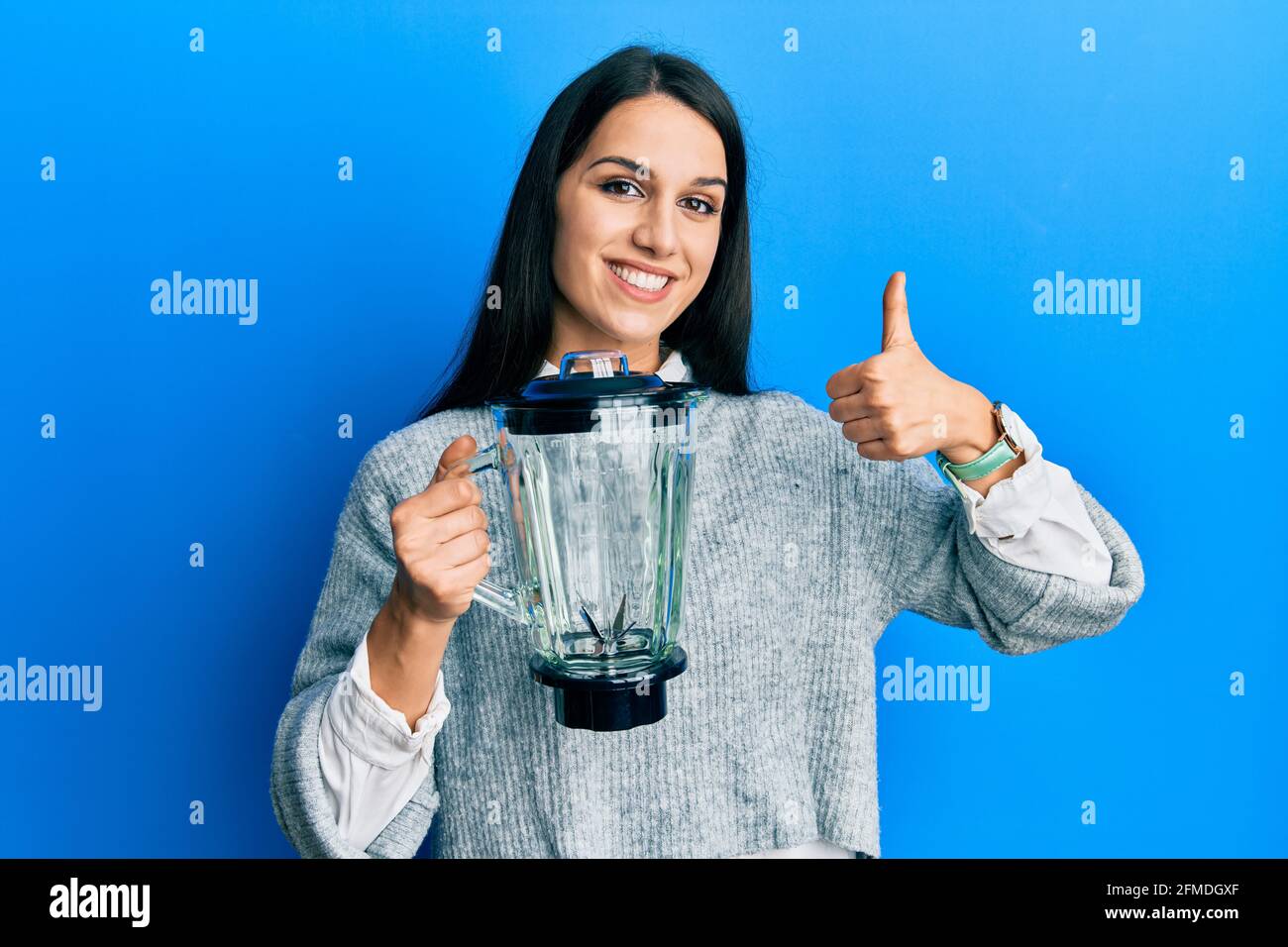 Young hispanic woman holding food processor mixer machine smiling happy ...