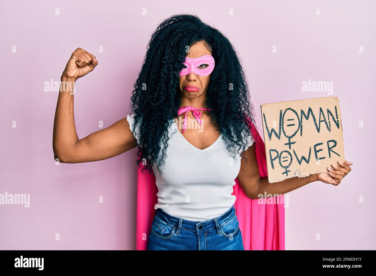 Middle age african american woman wearing super hero costume holding ...