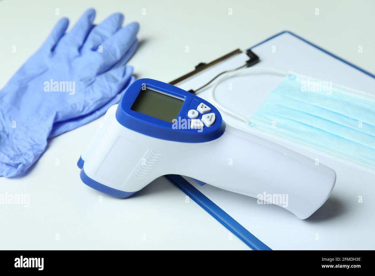 Medical tools and thermometer gun on white background Stock Photo - Alamy