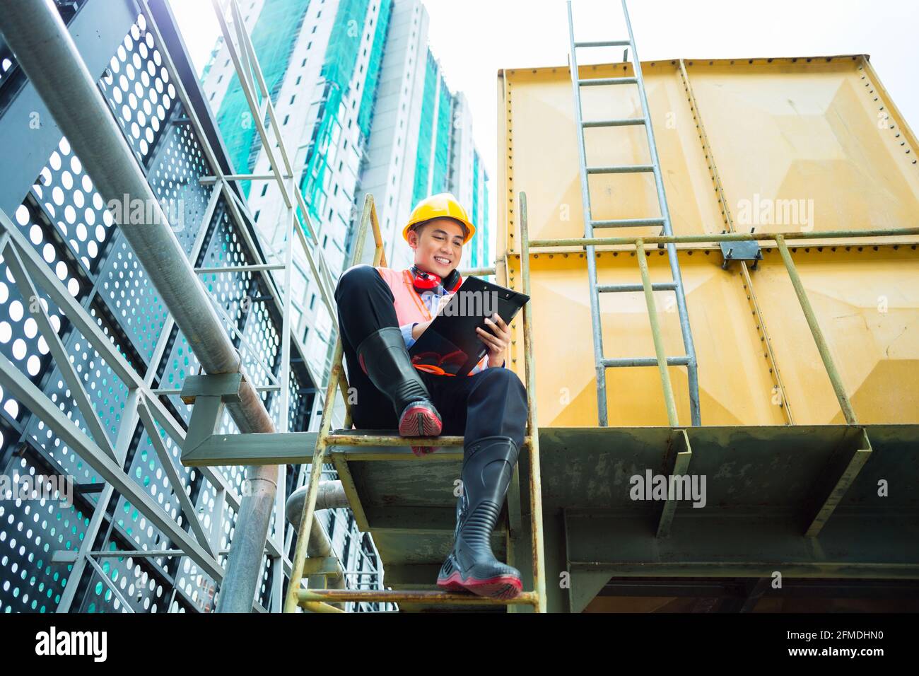 Asian Indonesian construction worker with helmet and safety vest on a ...