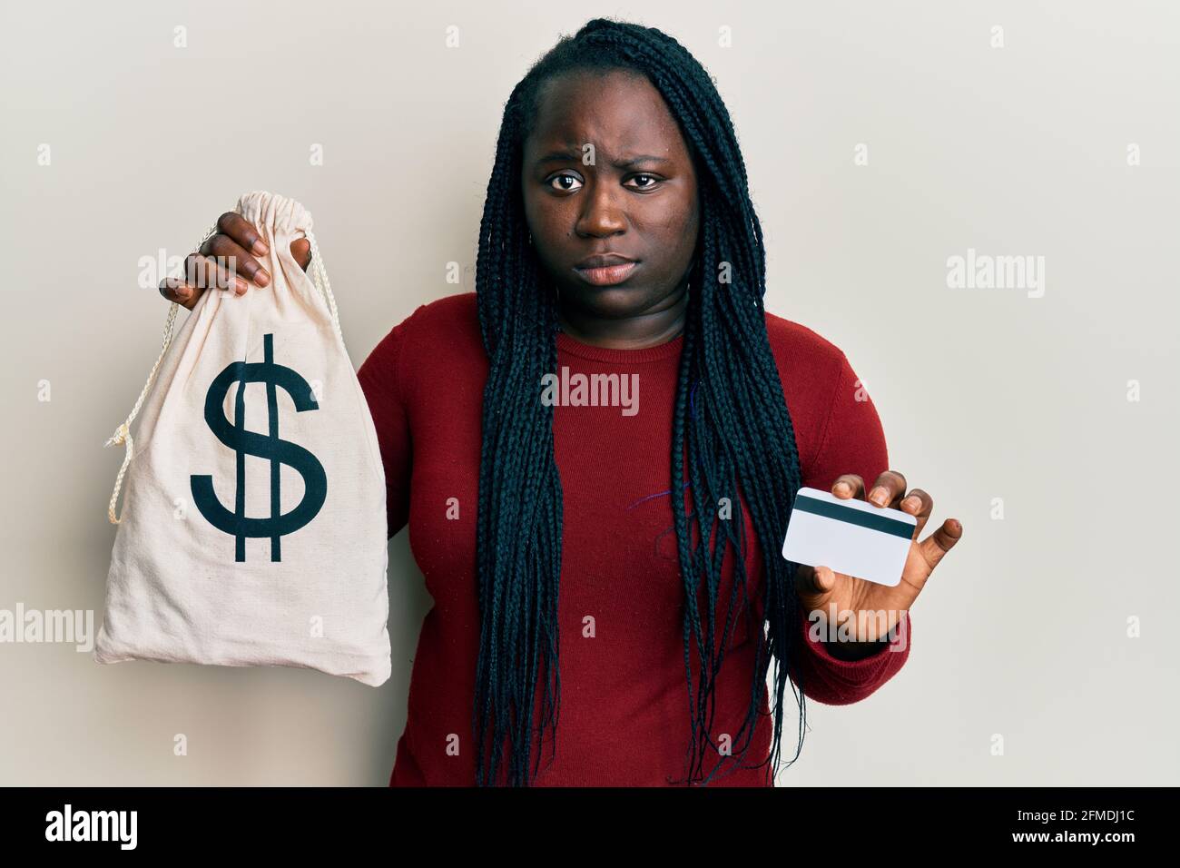 Young black woman with braids holding dollars bag and credit card ...