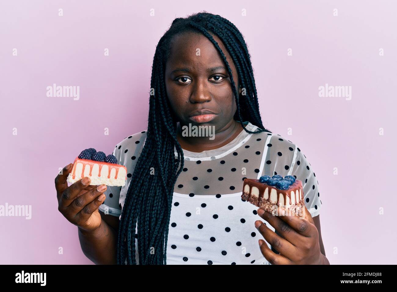 Young black woman with braids holding cheesecakes depressed and worry ...