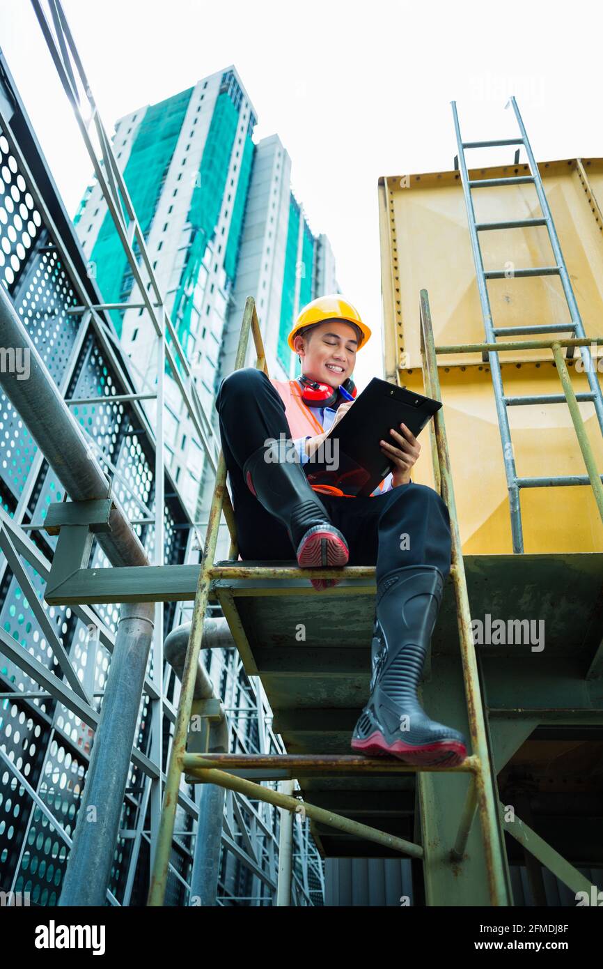 Asian Indonesian construction worker with helmet and safety vest on a ...